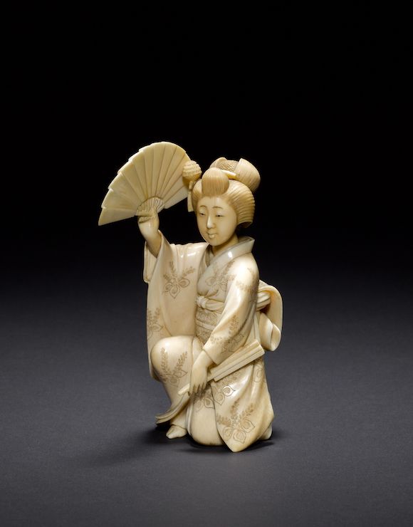 Bonhams : An ivory okimono of a seated Bijin or Geiko, holding two fans Meiji Period