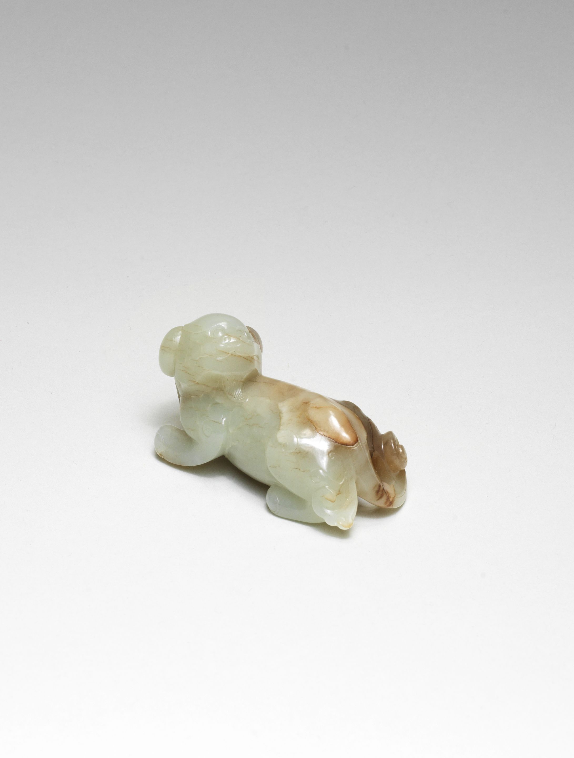 Bonhams : A PALE GREEN AND RUSSET JADE CARVING OF A DOG Ming Dynasty
