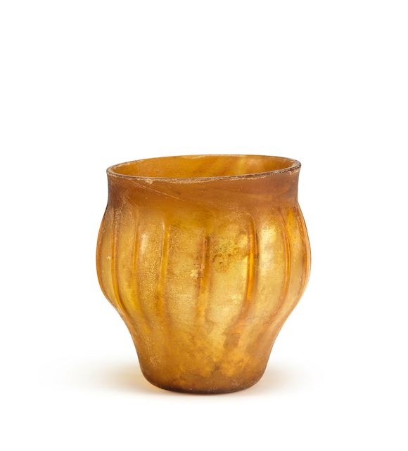 Bonhams : A Roman amber glass beaker with swollen body and pincered ribs